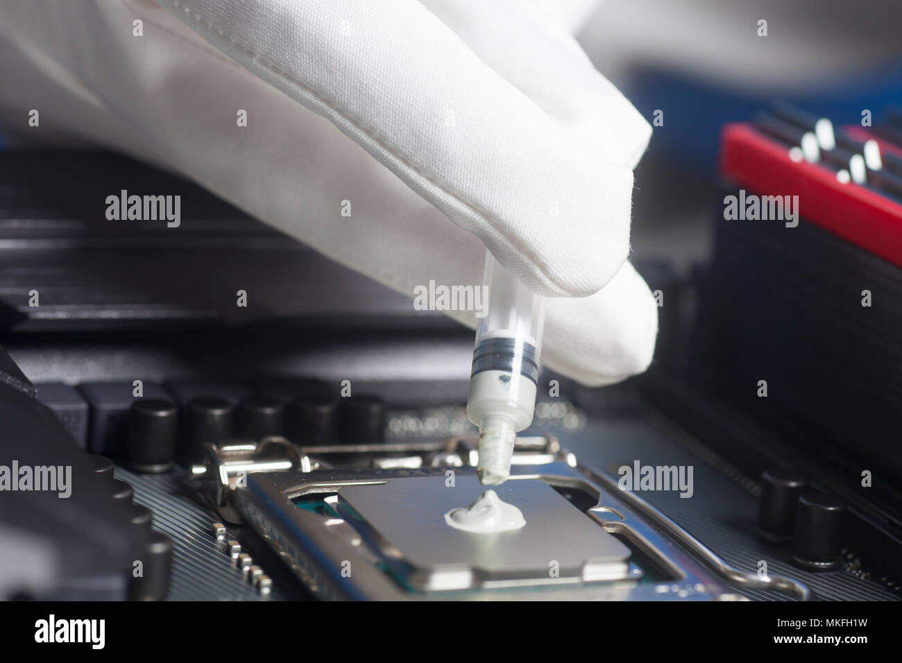 Hand wearing White Gloves with syringe applying thermal paste on the ...