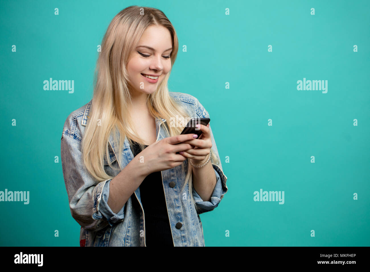 Happy young caucasian teen girl in denim cloth texting message on ...