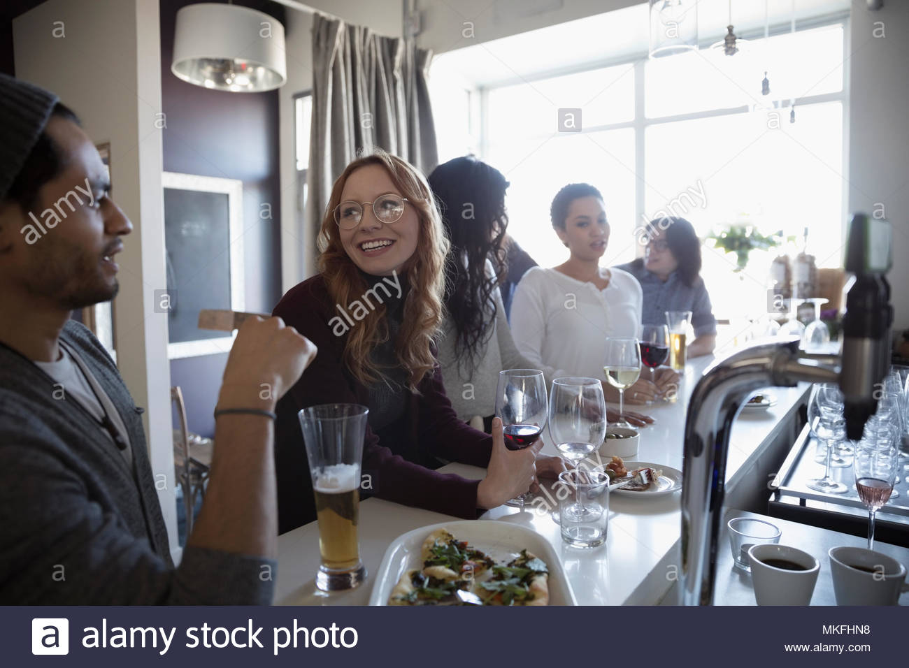 Group of friends drinking and eating together in a restaurant hi-res ...