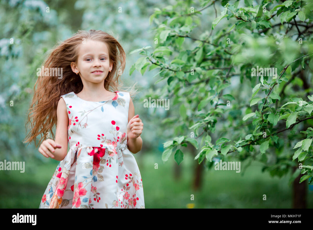 Adorable little girl in blooming apple tree garden on spring day Stock Photo - Alamy