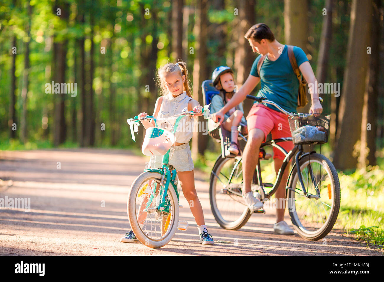 Happy family biking outdoors at the park Stock Photo - Alamy