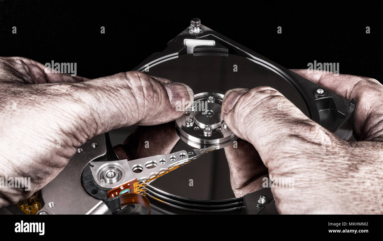Dirty hands on open hard disk drive. Artistic close-up with mirroring ...