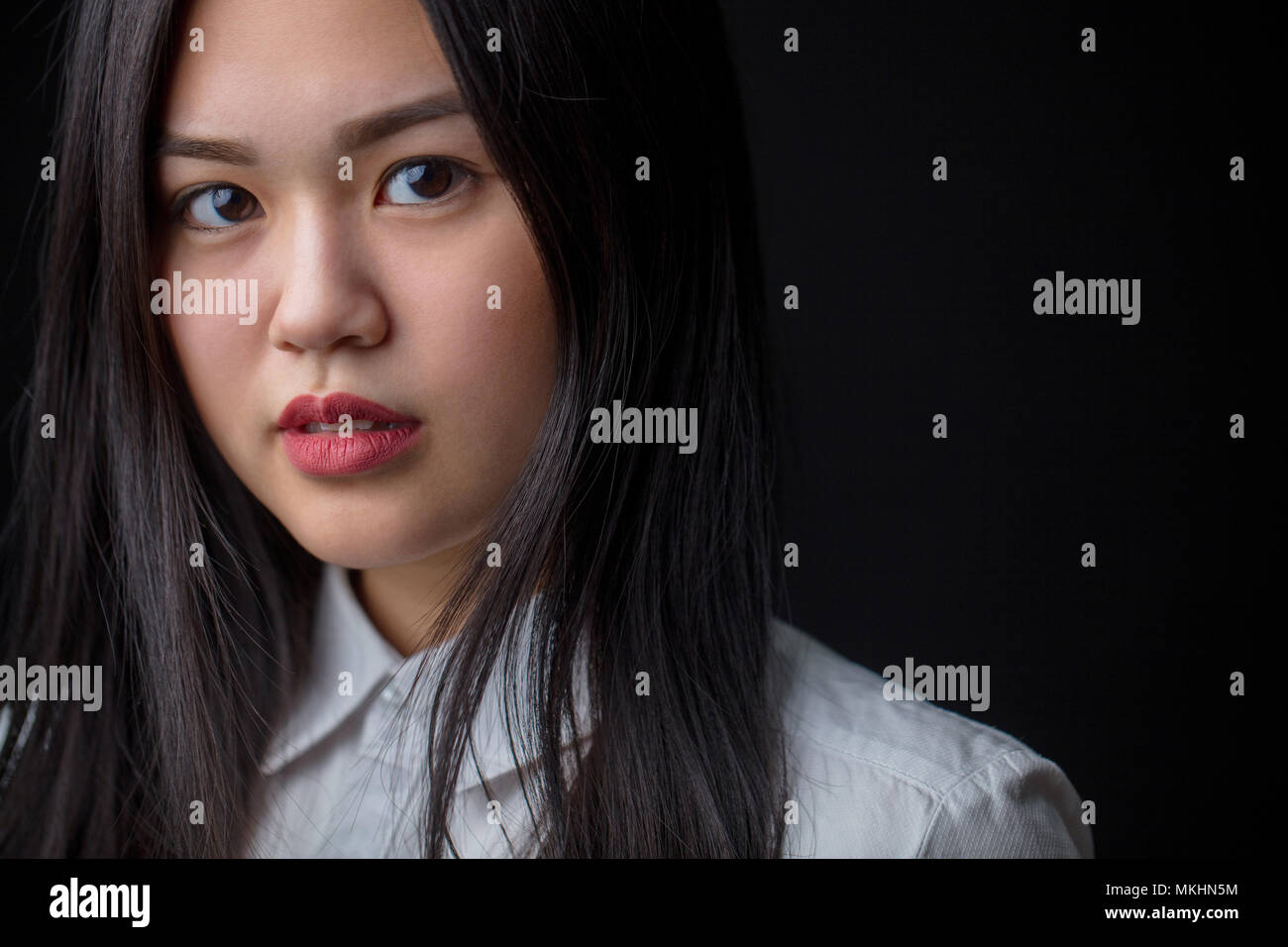 Close up of appealing asian woman with piercing eyes against black ...