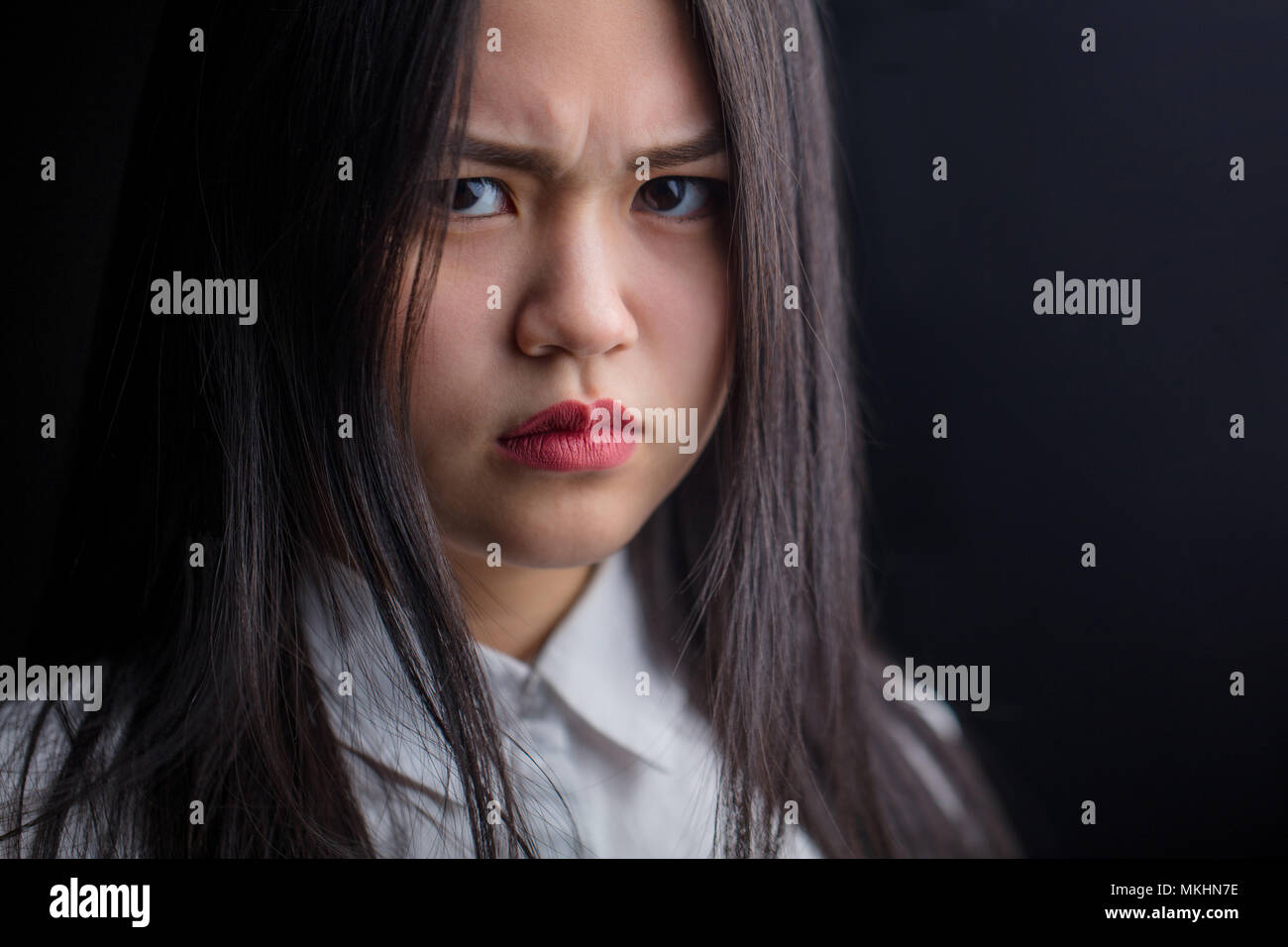 Close up of displeased asian woman with frowny face and resentful look ...