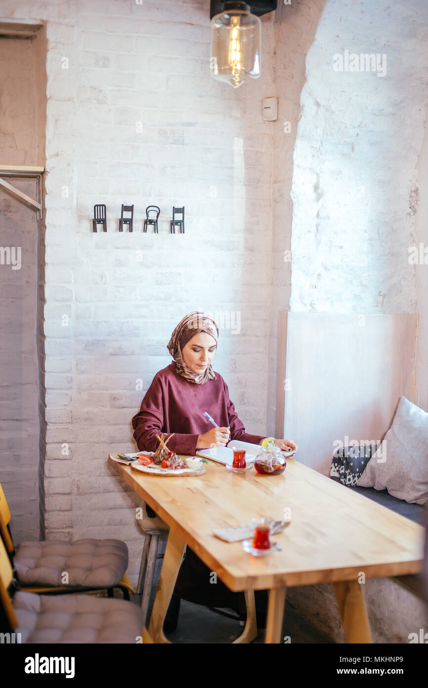 Muslim woman writing love diary in cafe Stock Photo - Alamy