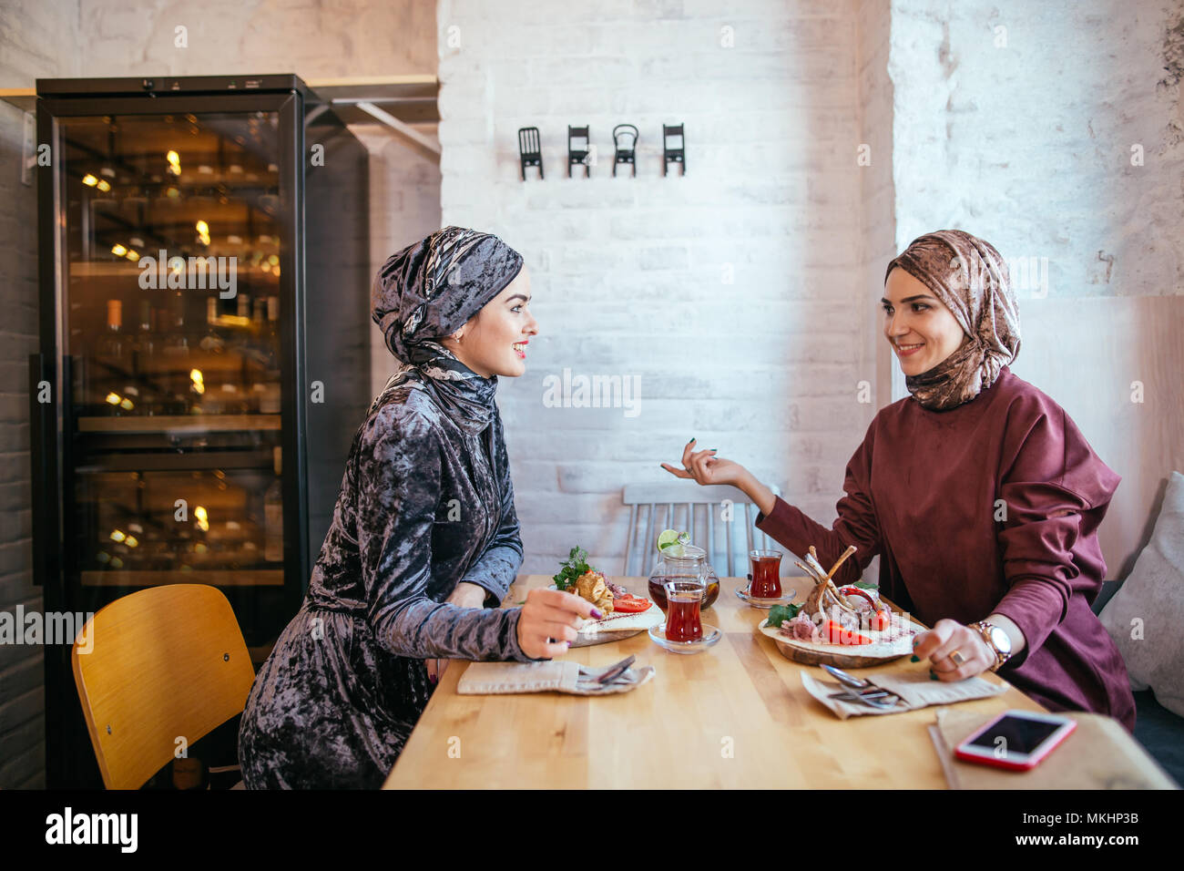 Two Muslim Friends Enjoying food while sitting in cafe Stock Photo - Alamy