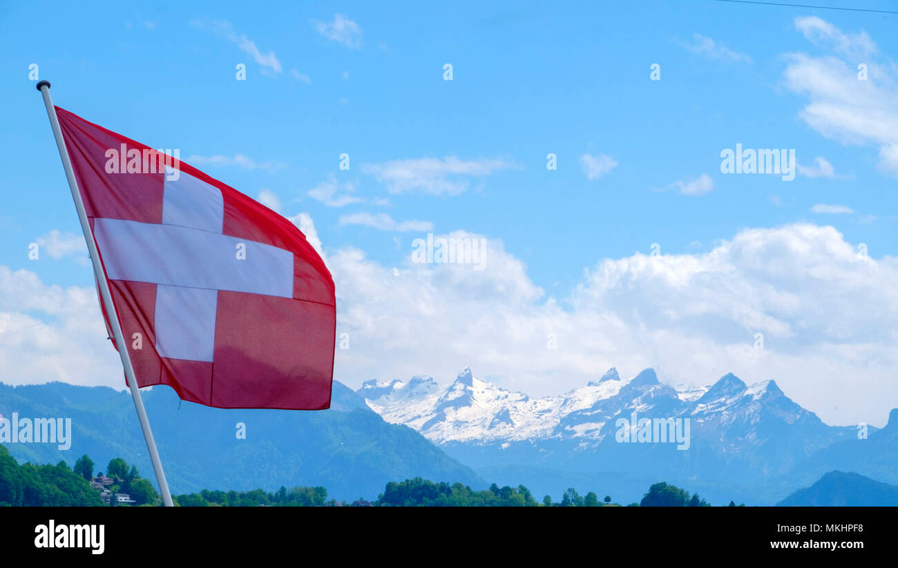 Swiss flag waving in the wind with snow covered mountain as background ...