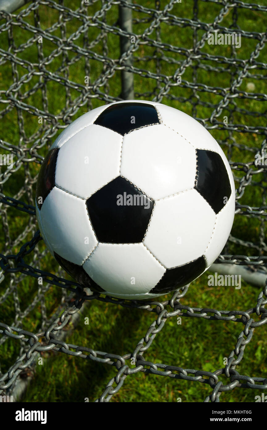 soccer ball classic black and white on the top of a chain goal in the ...