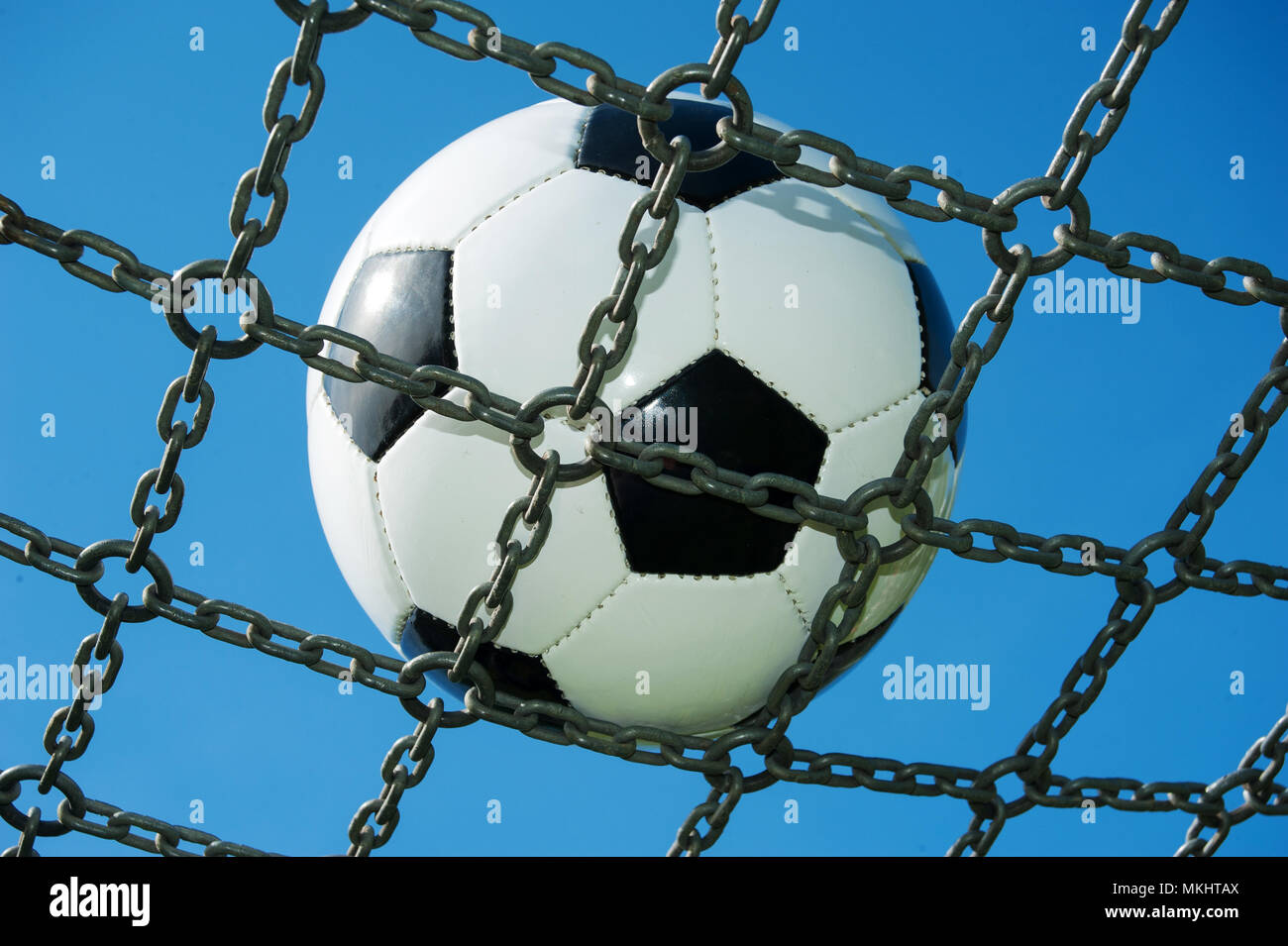 soccer ball classic black and white on the top of a chain goal in the ...