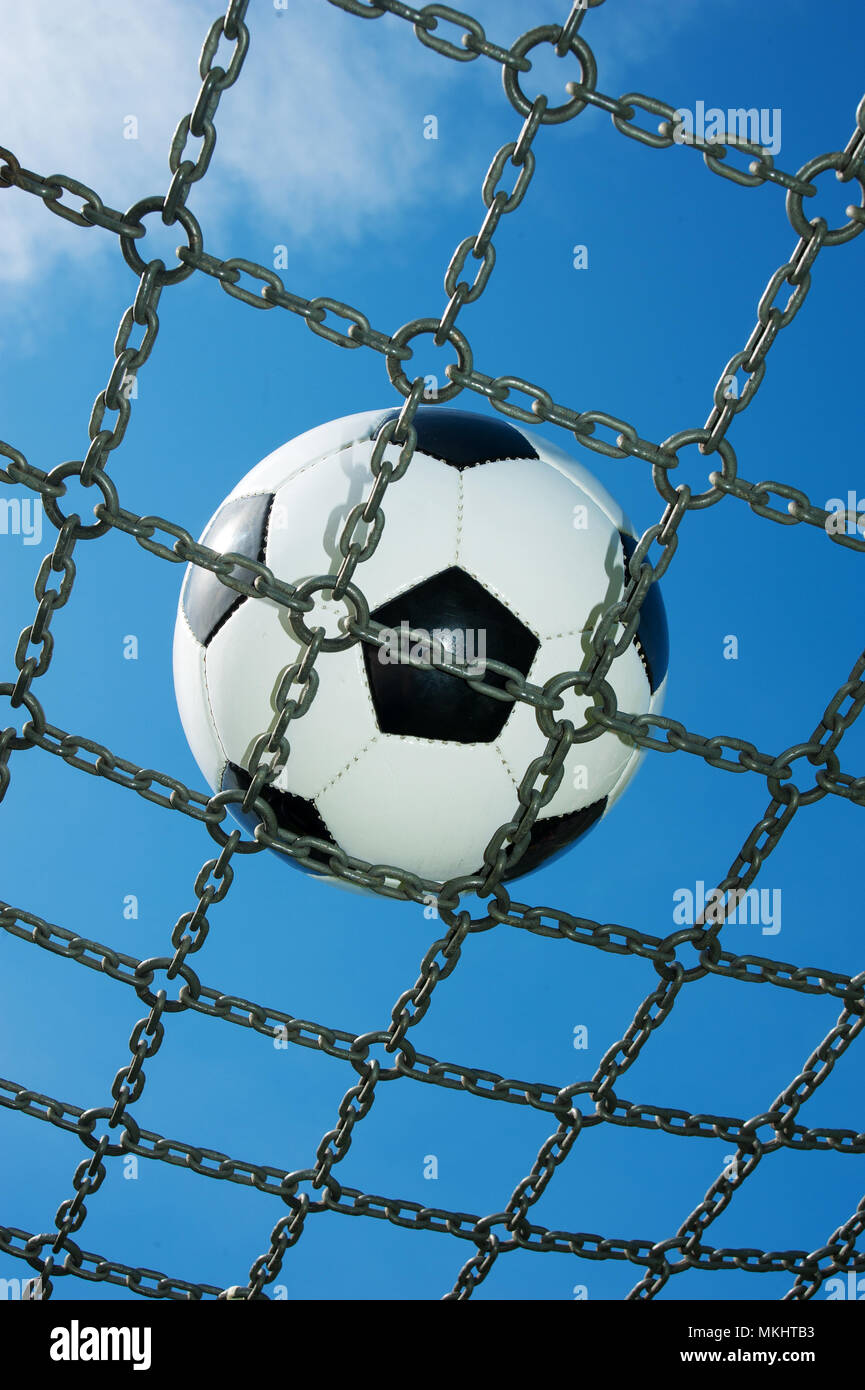 soccer ball classic black and white on the top of a chain goal in the ...