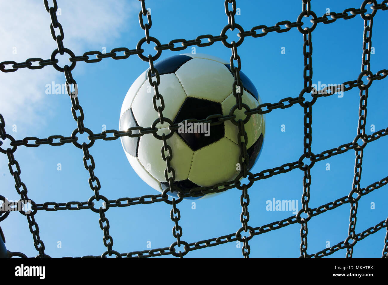 soccer ball classic black and white on the top of a chain goal in the ...
