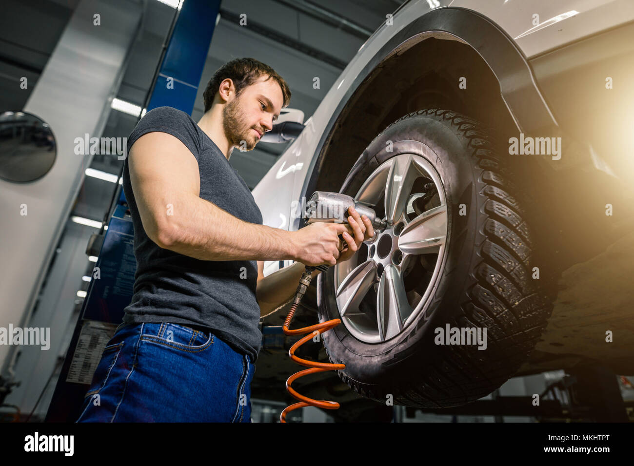 car mechanic changing car wheel in auto repair garage Stock Photo - Alamy