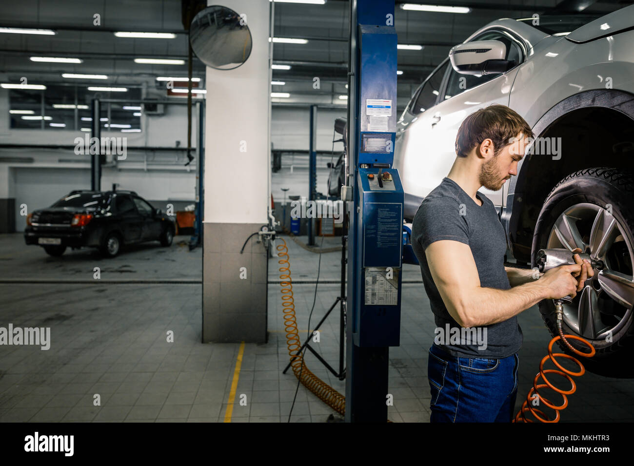 Mechanic changing wheel on car with pneumatic tool Stock Photo - Alamy