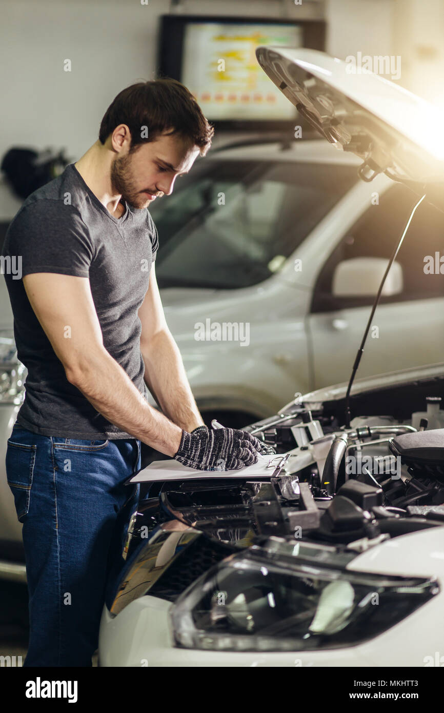Automechanic controlling car with checklist in repair garage Stock ...