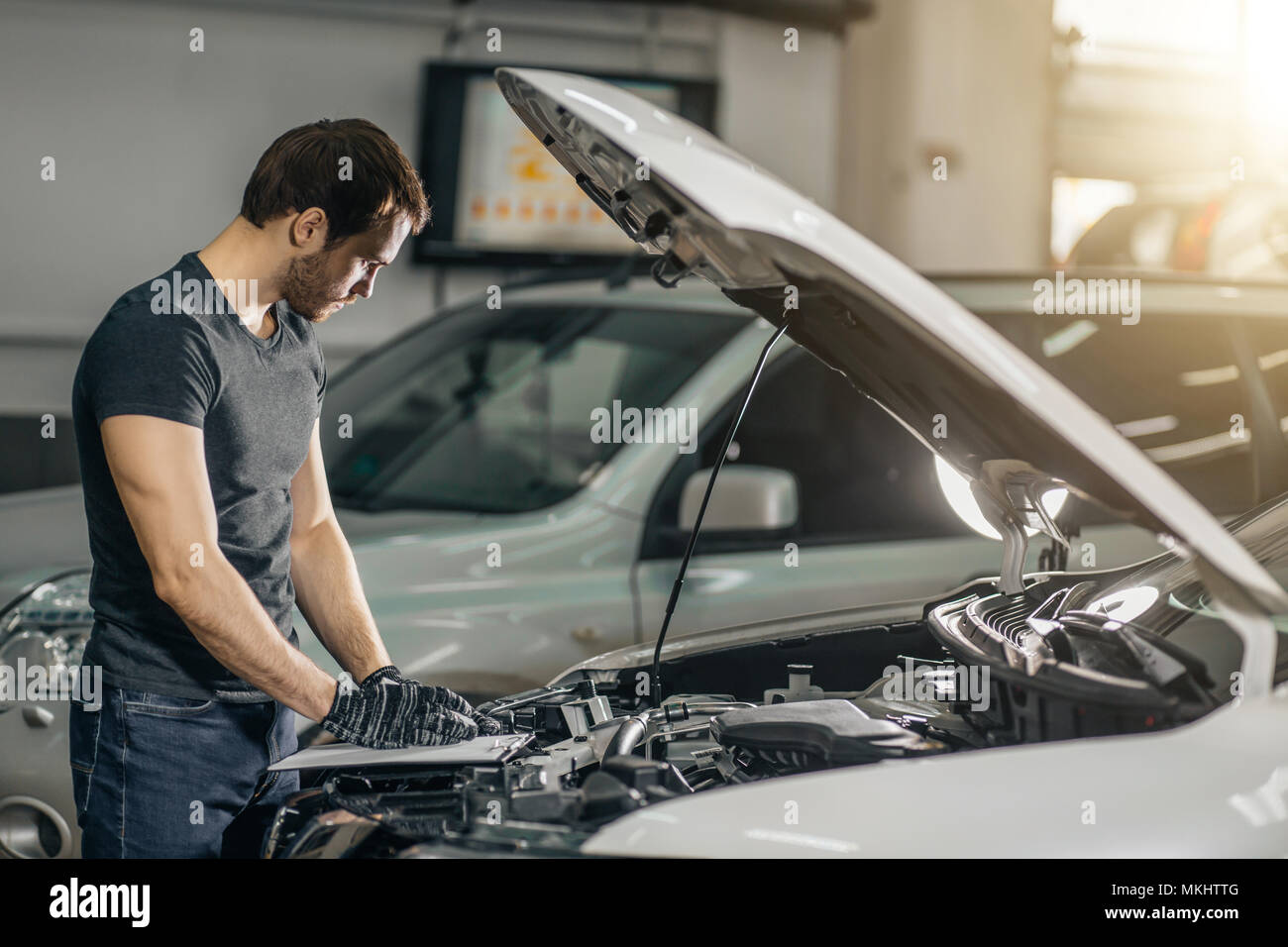 Mechanic perform vehicle checkup and make notes in notepad in garage ...