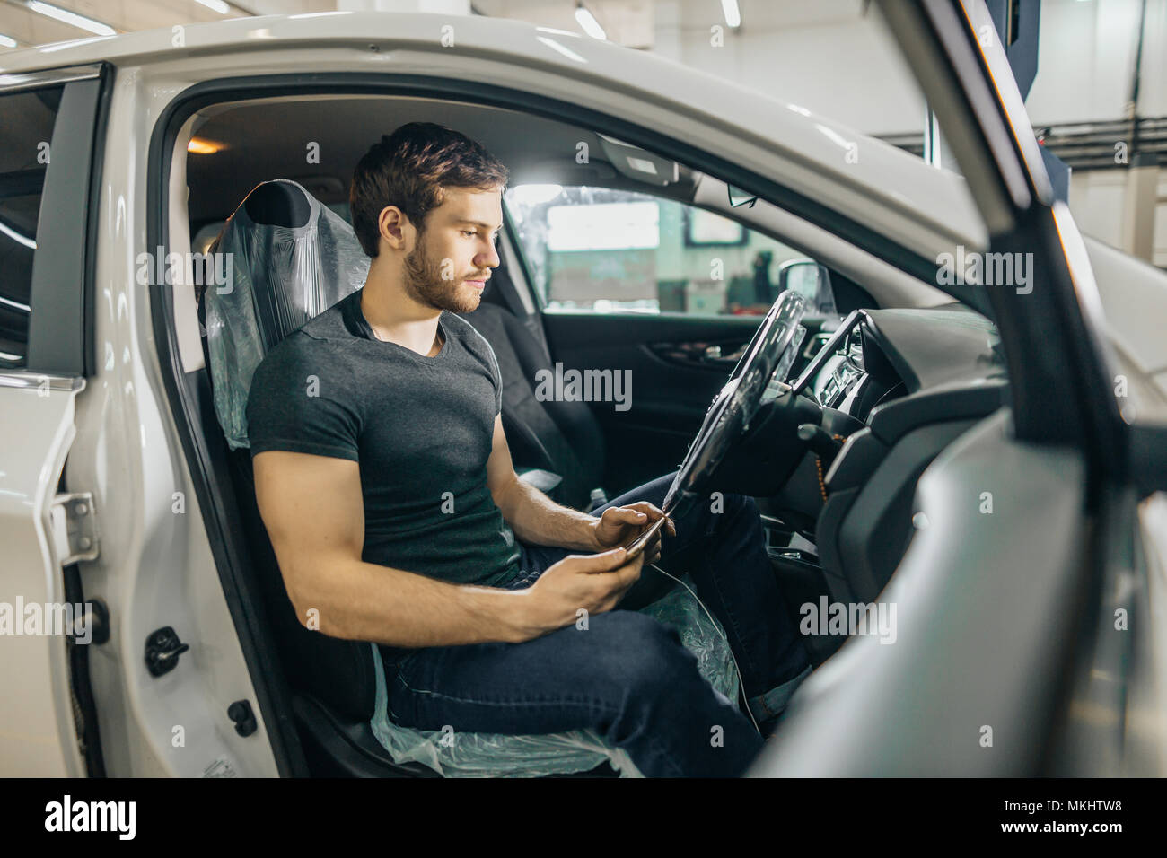 mechanic sitting in car doing diagnostics on digital tablet Stock Photo ...