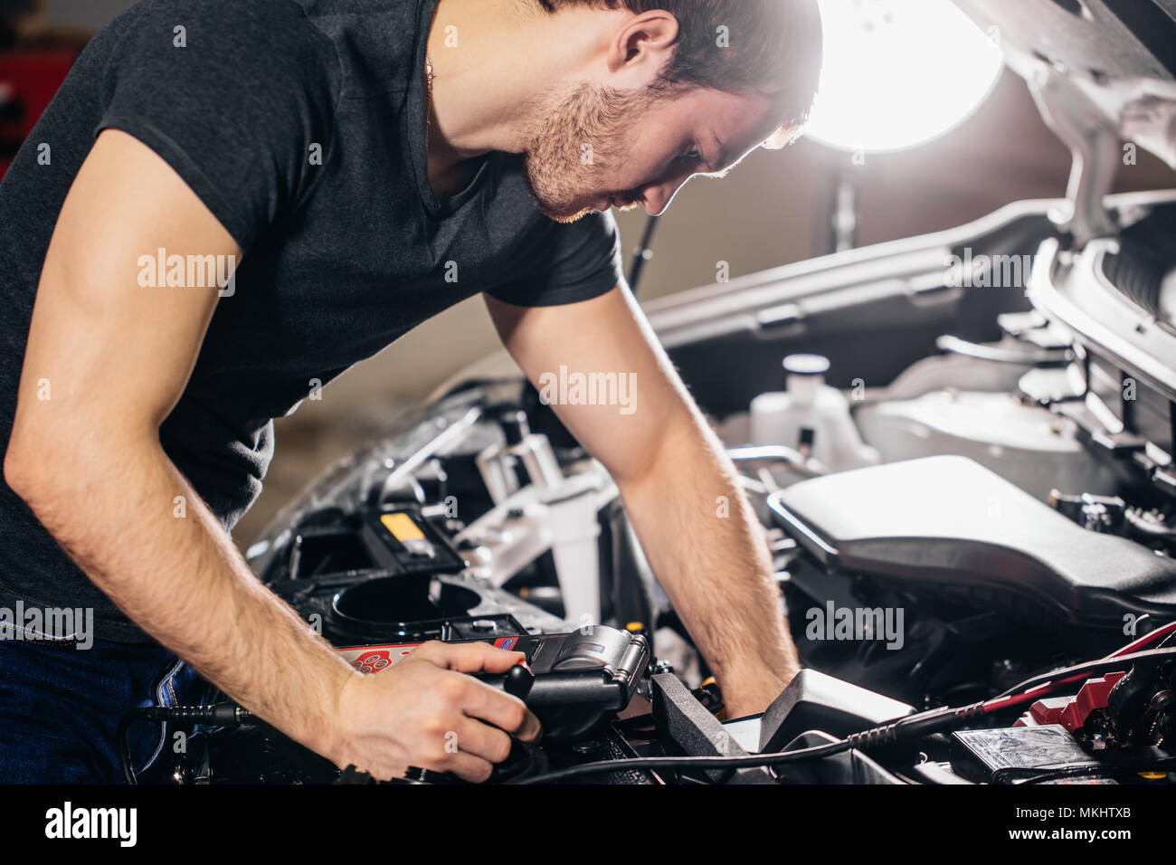 Car mechanic using electrical tool for testing car system in garage ...