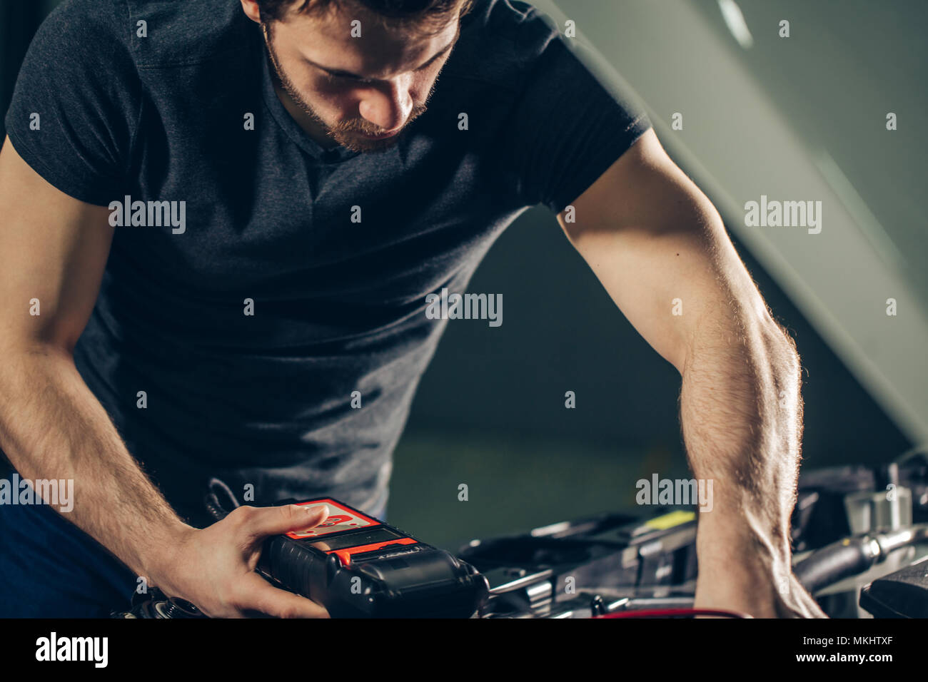 Car mechanic using electrical tool for testing car system in garage ...