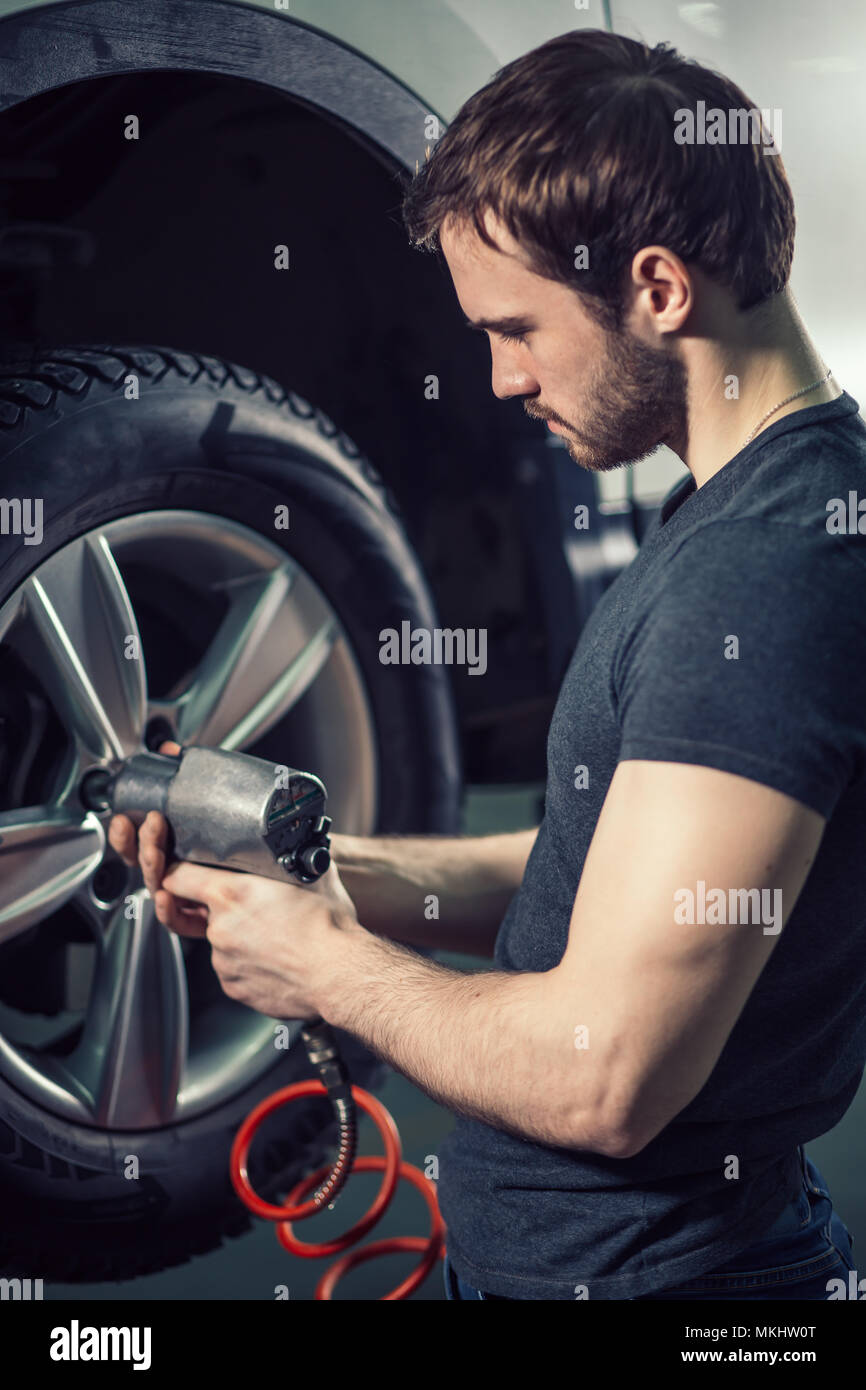 car mechanic changing car wheel in auto repair garage Stock Photo - Alamy