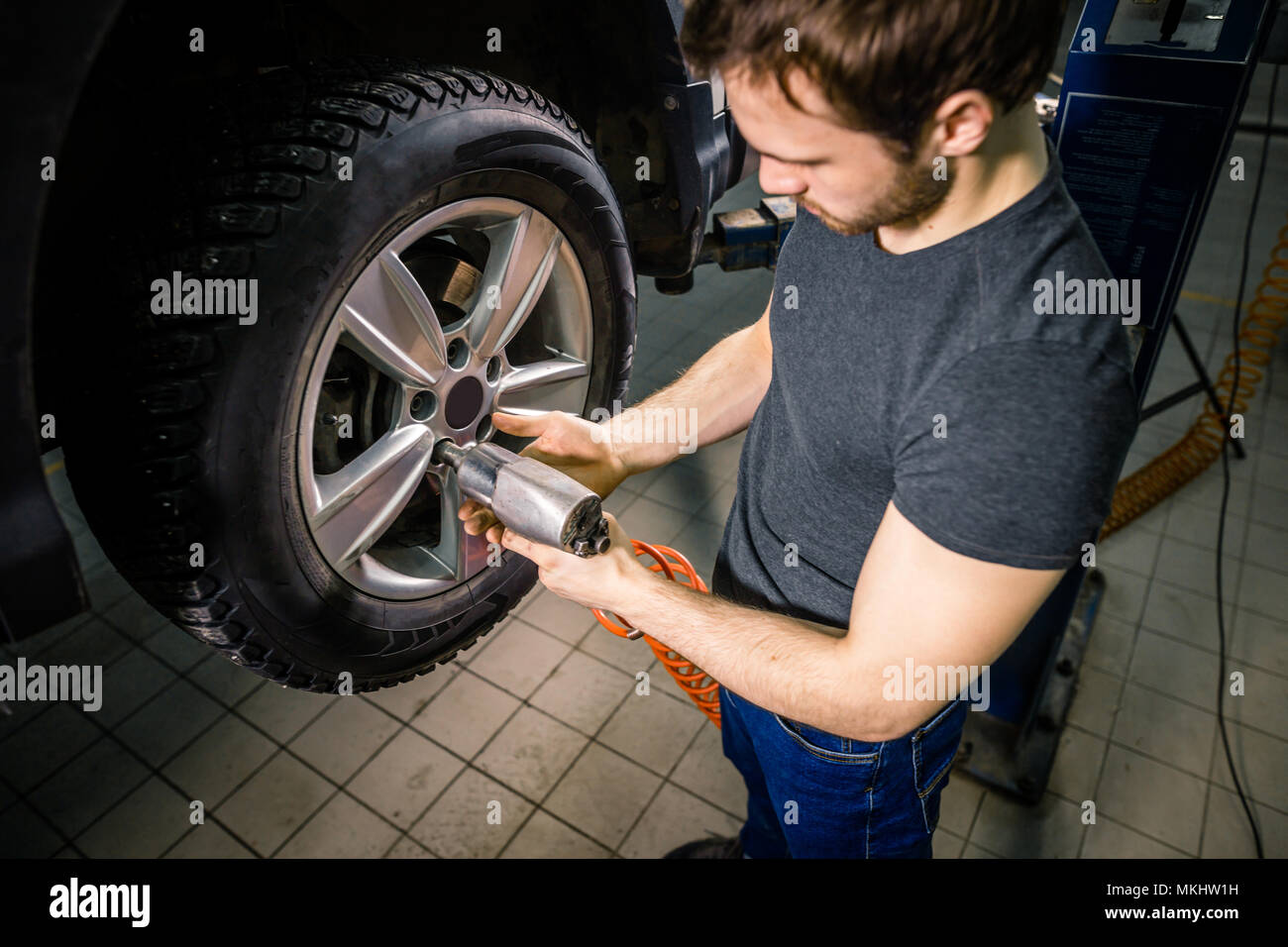 car mechanic changing car wheel in auto repair garage Stock Photo - Alamy