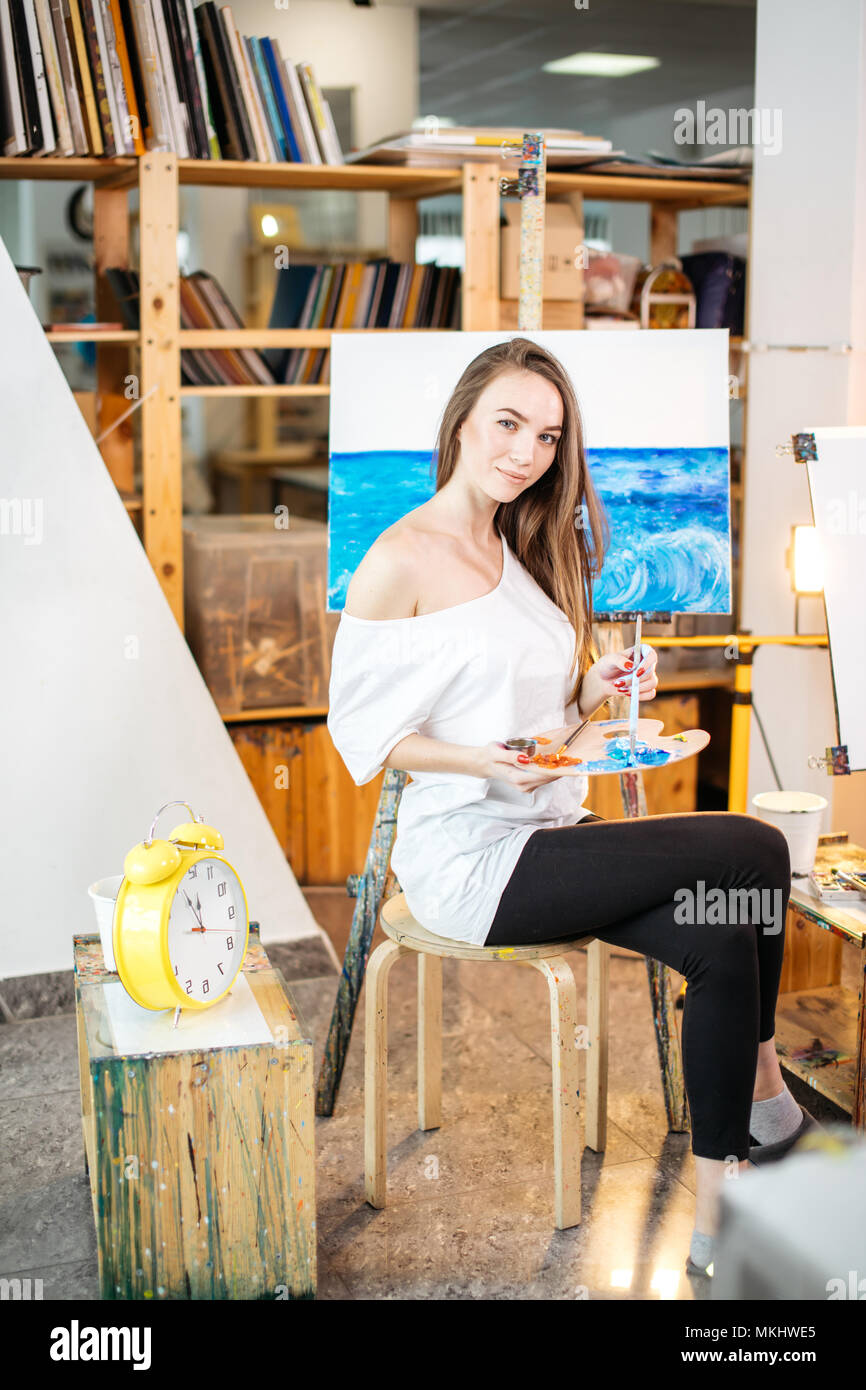 Painting process at workshop . Young professional female artist looking ...