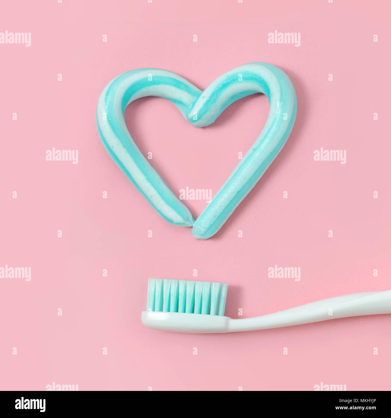 Toothbrushes and turquoise color toothpaste in shape of heart on pink ...