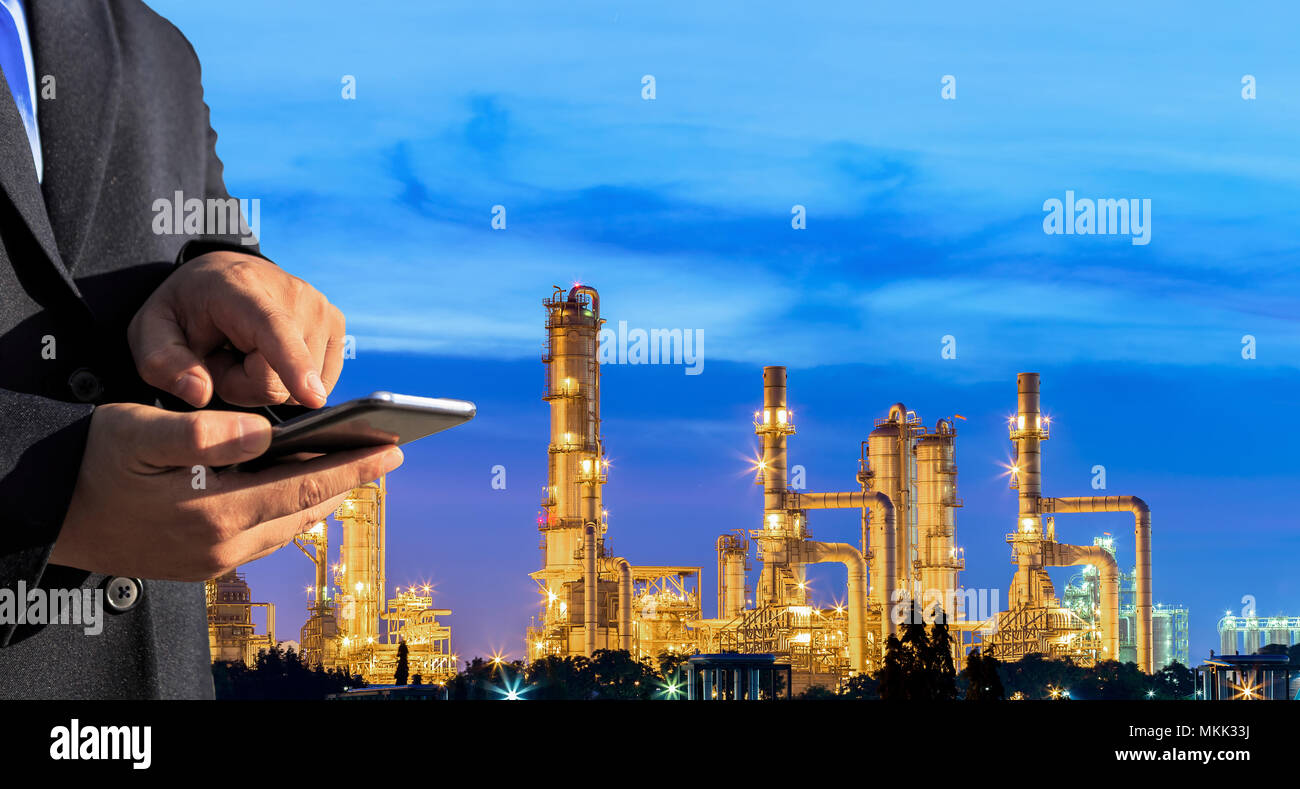 businessman checking oil refinery industry plant by smart phone in the ...