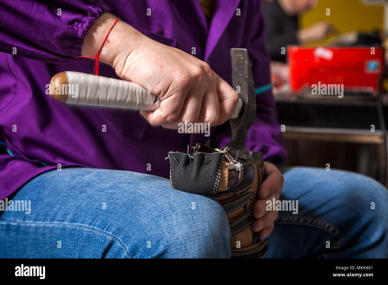 Close-up of a young man worker in jeans makes a soles of children's ...