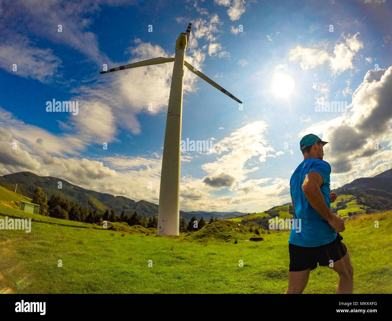 Male athlete running in mountains at wind turbine background Stock ...