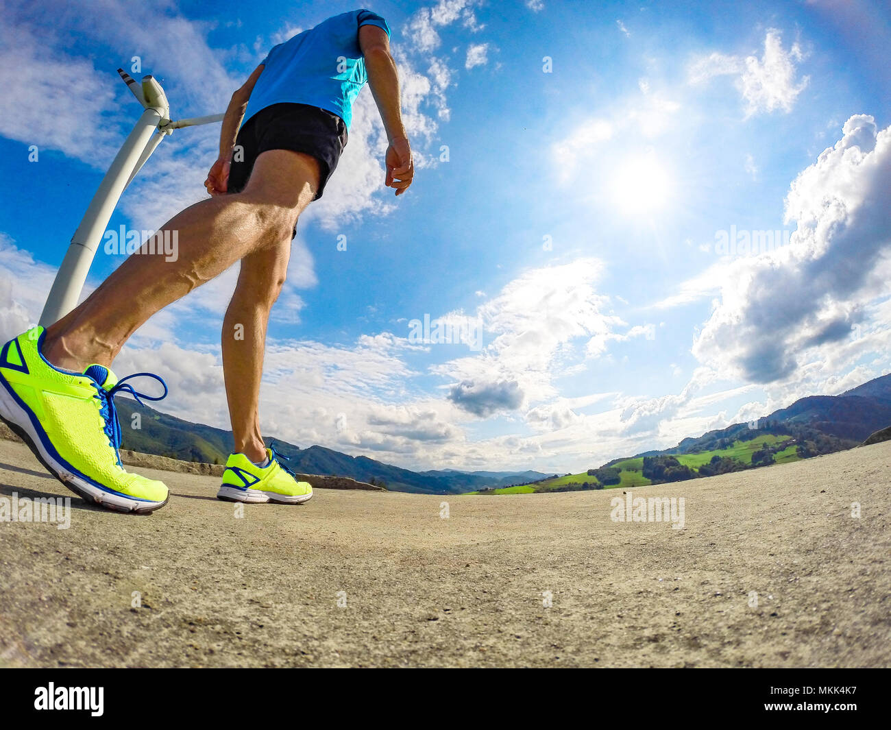 Male athlete runner walking in mountains at wind turbine background ...