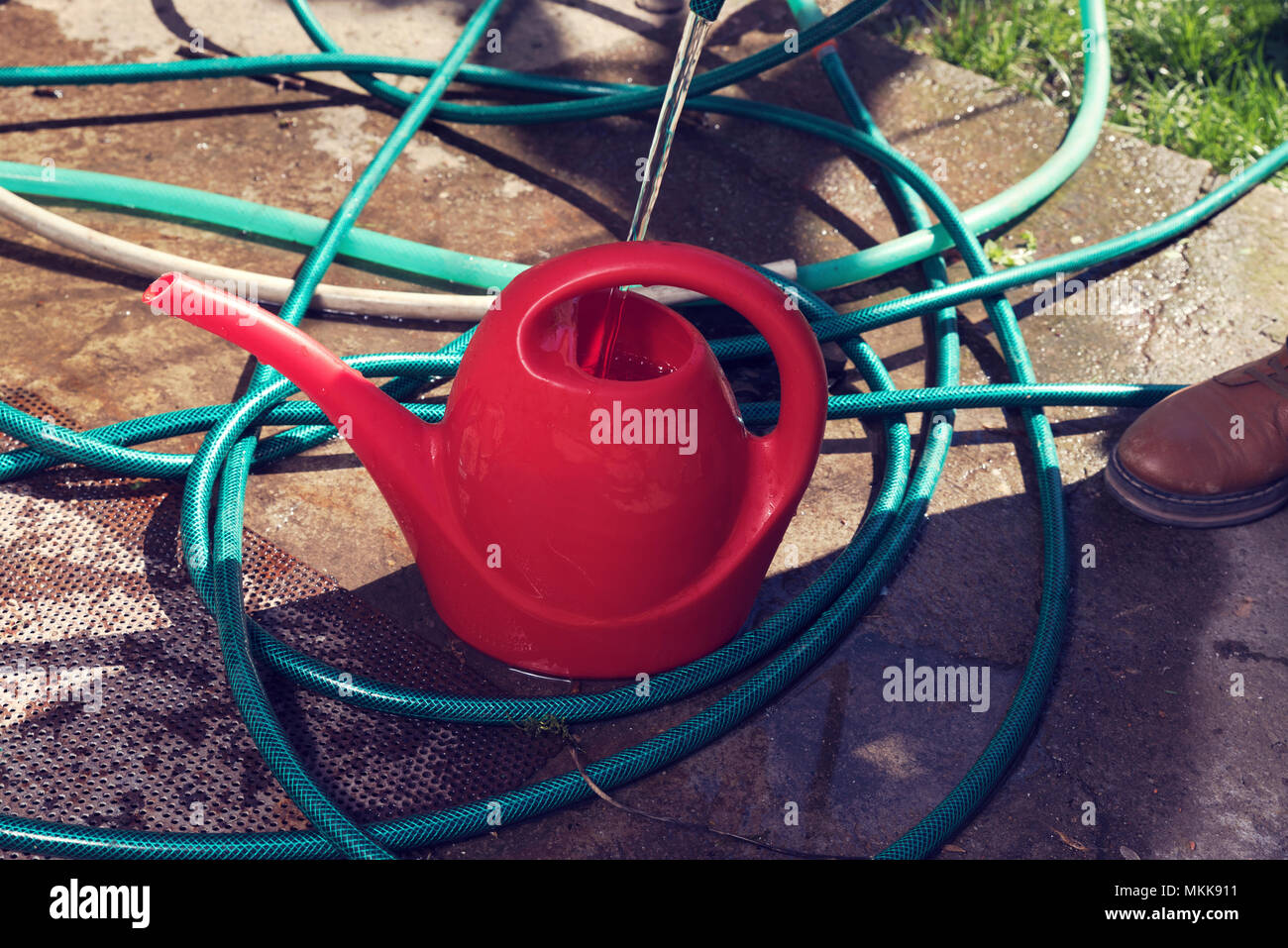 Filling red water can wirh water Stock Photo - Alamy