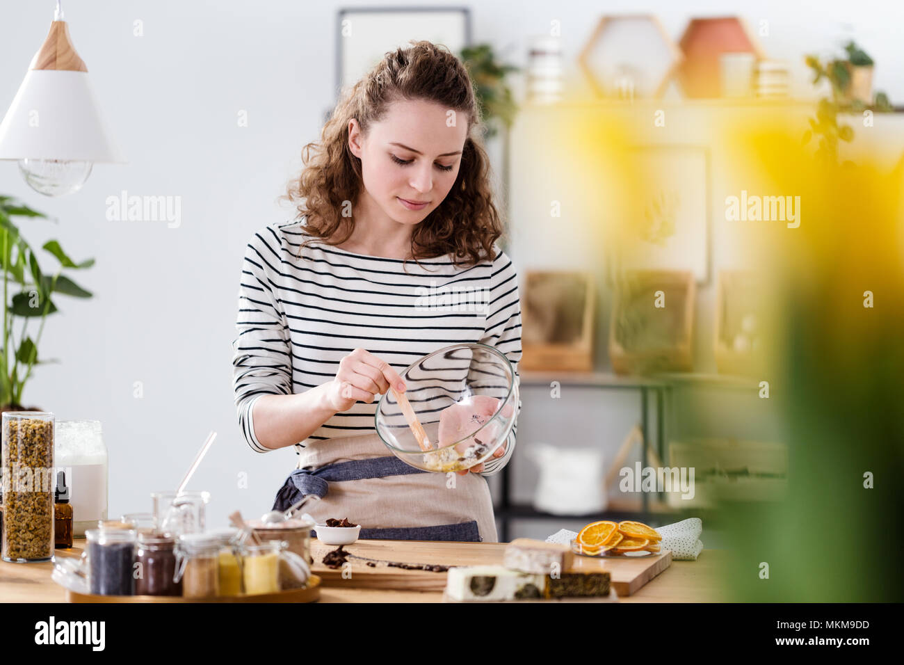 Vegan woman mixing natural ingredients while making organic face cream ...