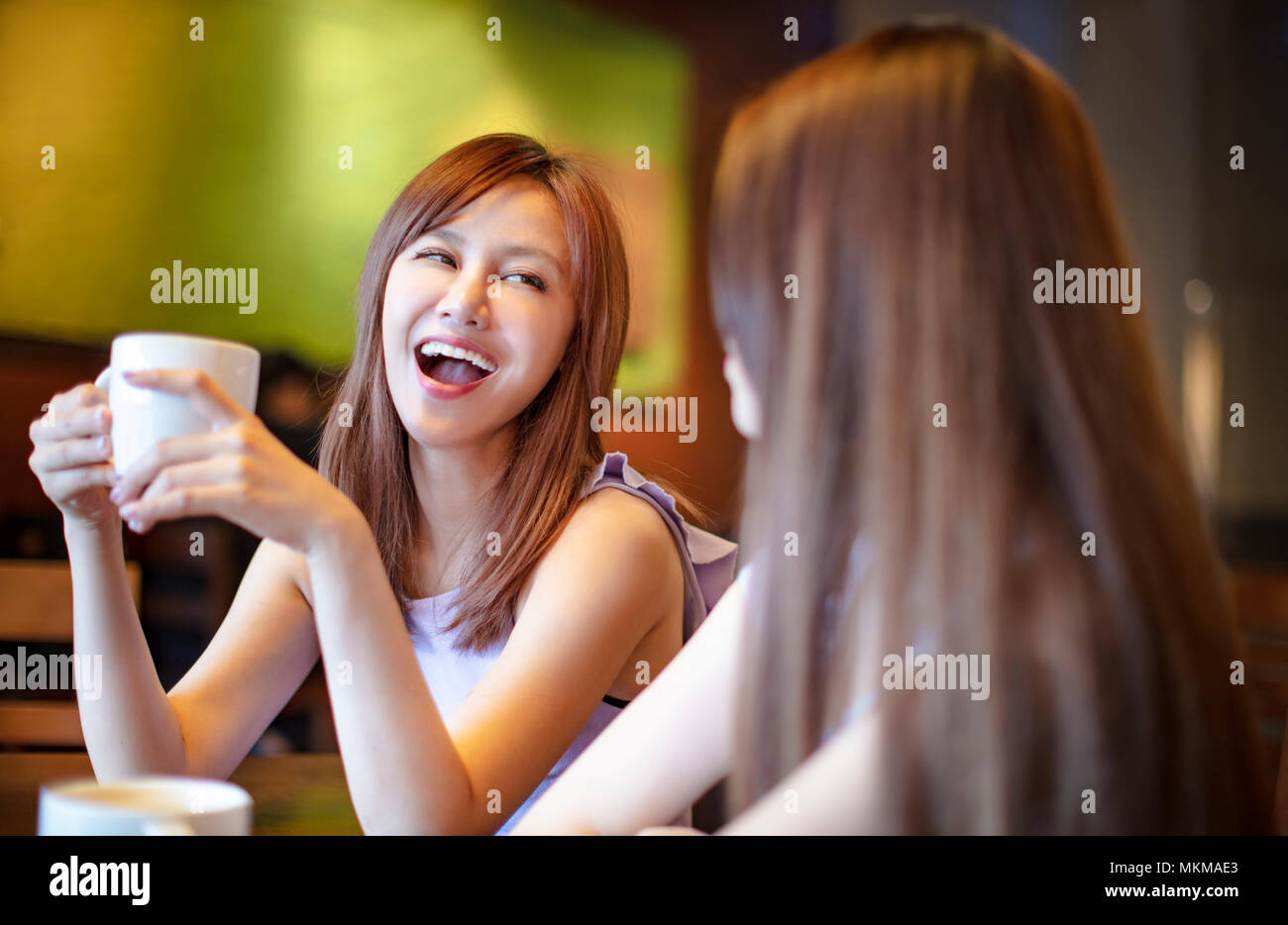 happy young women talking in coffee shop Stock Photo - Alamy