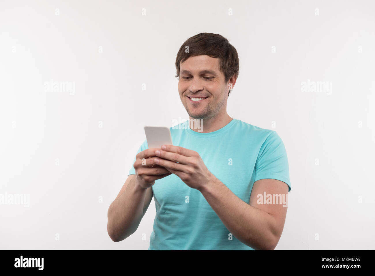Positive delighted man using his mobile phone Stock Photo - Alamy