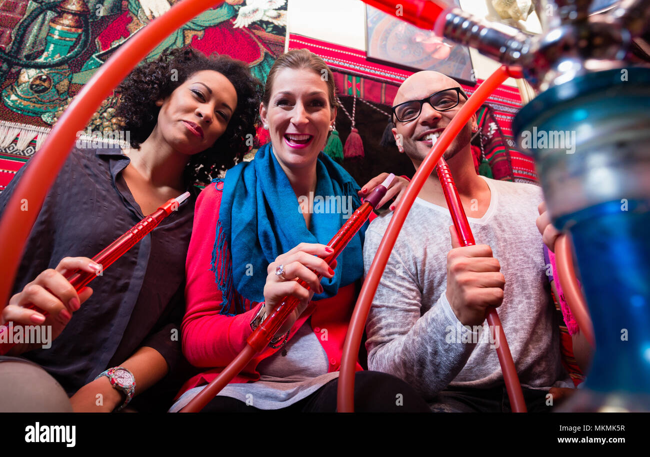 Friends smoking a hookah in shisha lounge Stock Photo - Alamy