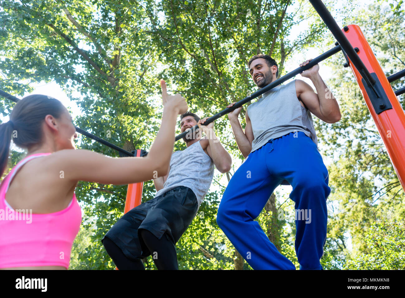 Two young men repeating pull-up exercise during upper-body routine ...