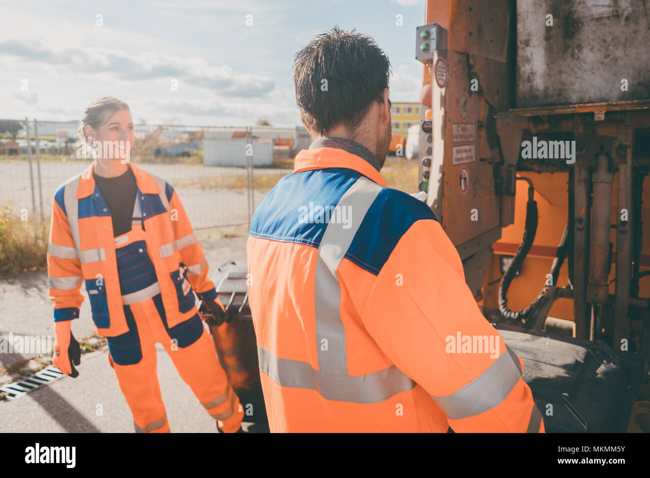 Garbage man and women cleaning dustbins into waste truck Stock Photo ...