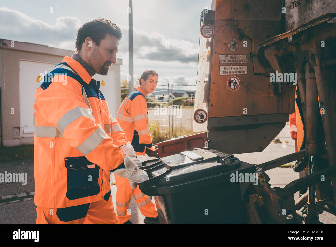 Garbage man and women cleaning dustbins into waste truck Stock Photo ...