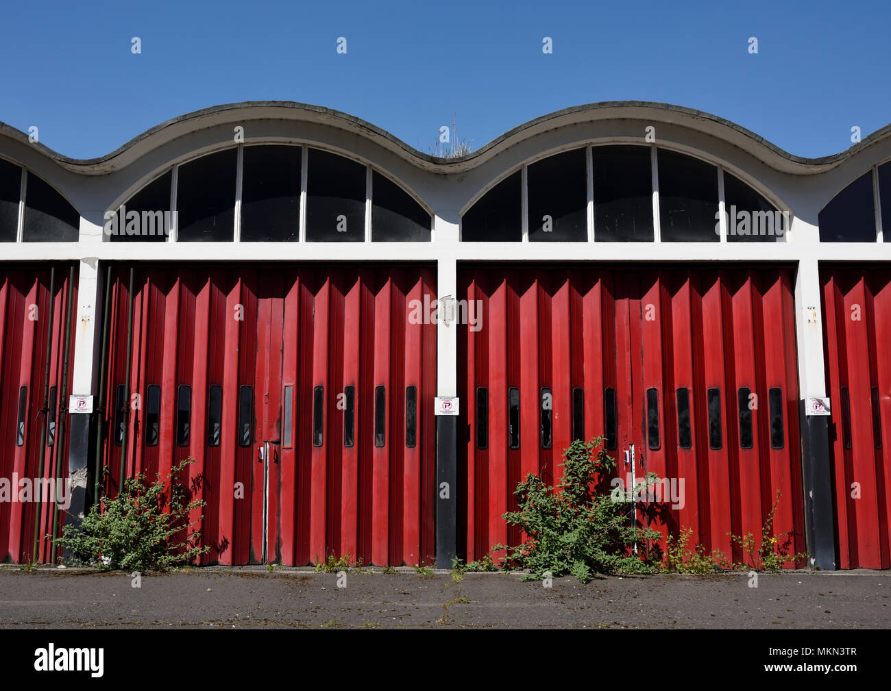 Red concertina folding doors and curvilinear roof on disused fire ...