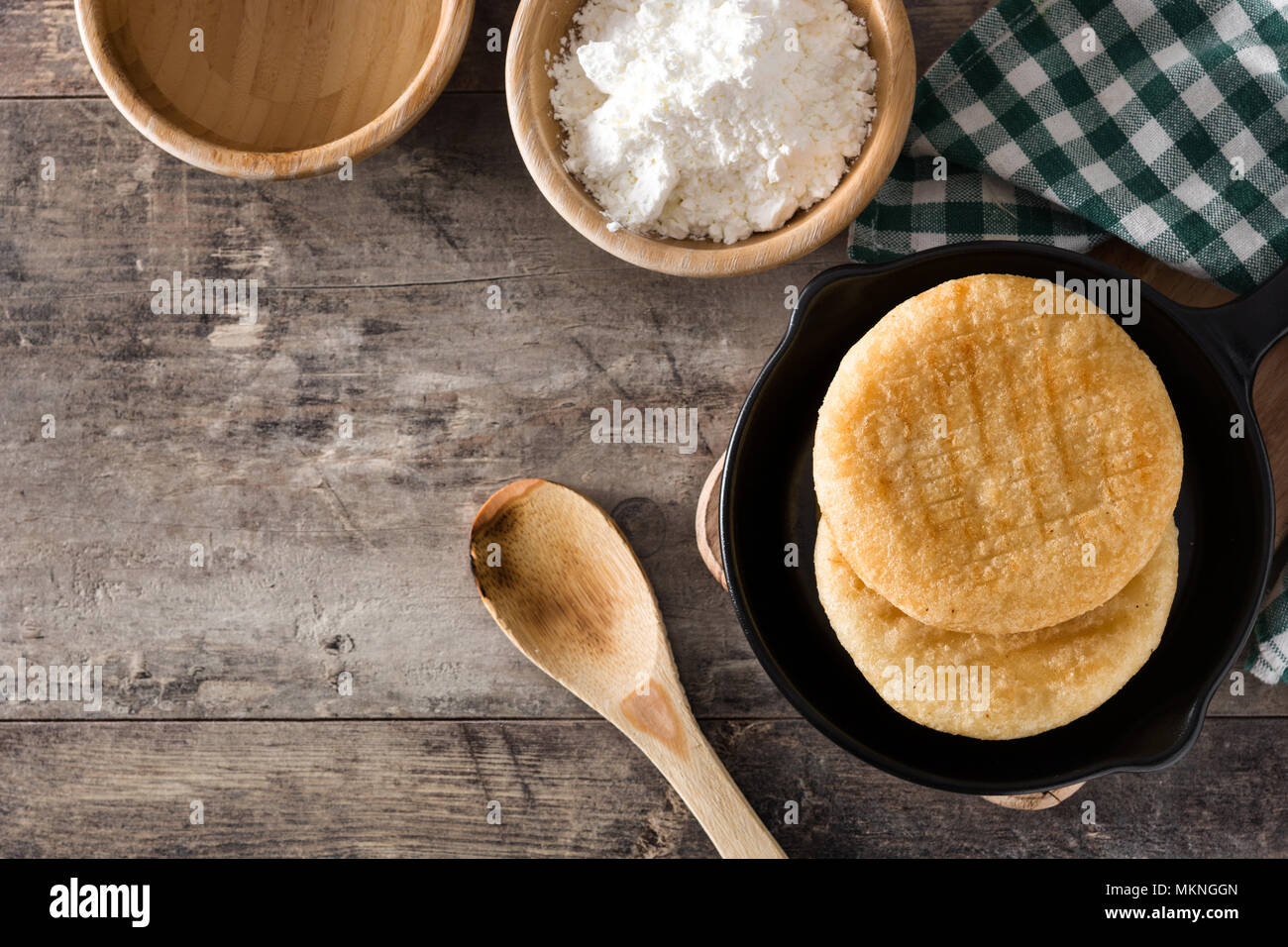 Arepas in iron pan on wooden table. Venezuelan typical food. Top view ...