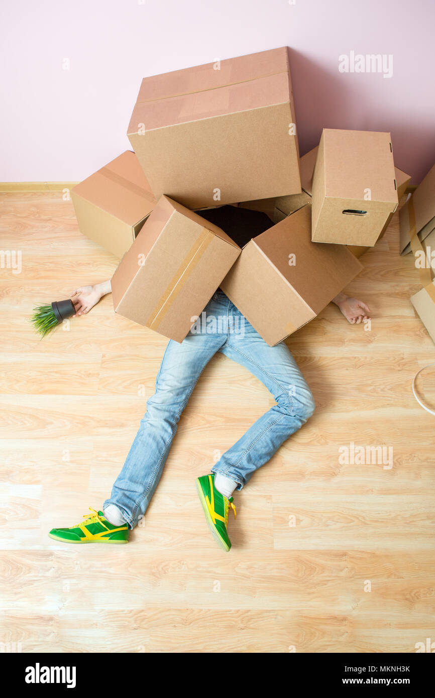 Photo of man in jeans lying under cardboard boxes Stock Photo - Alamy