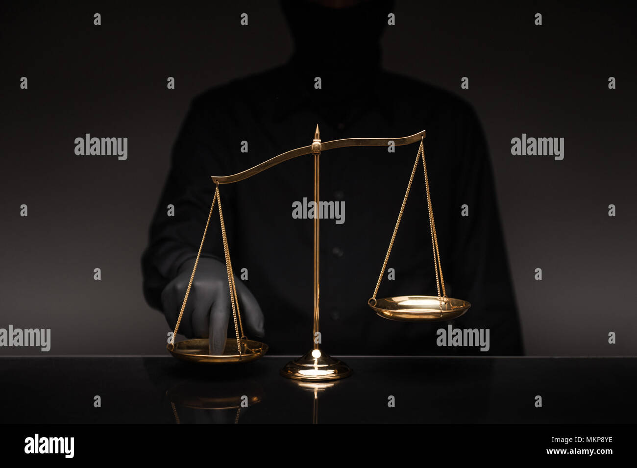 Someone wearing black shirt pressing the imbalance scale on black glass ...