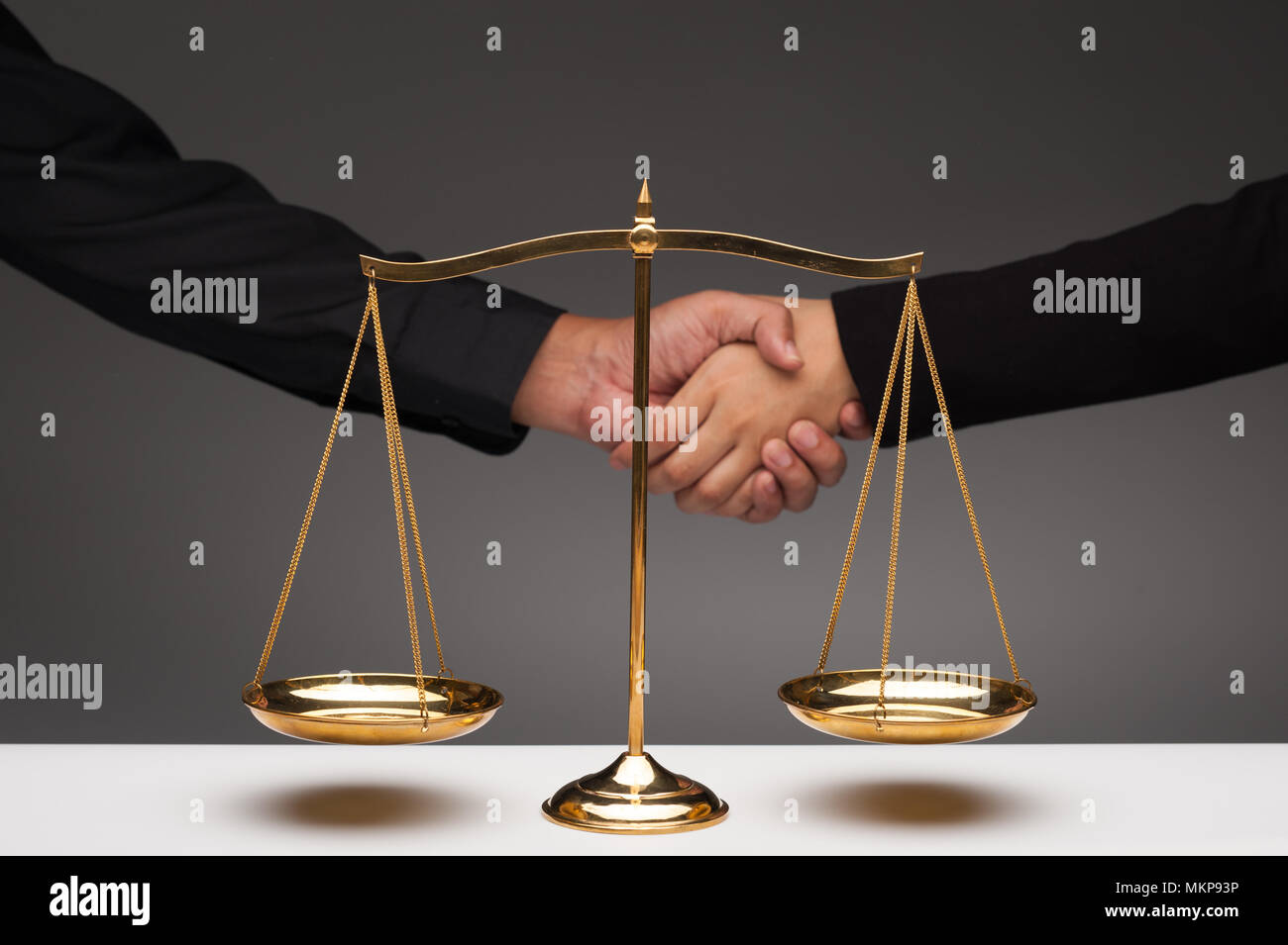 Close up of people shaking hands together in front of scale balance ...