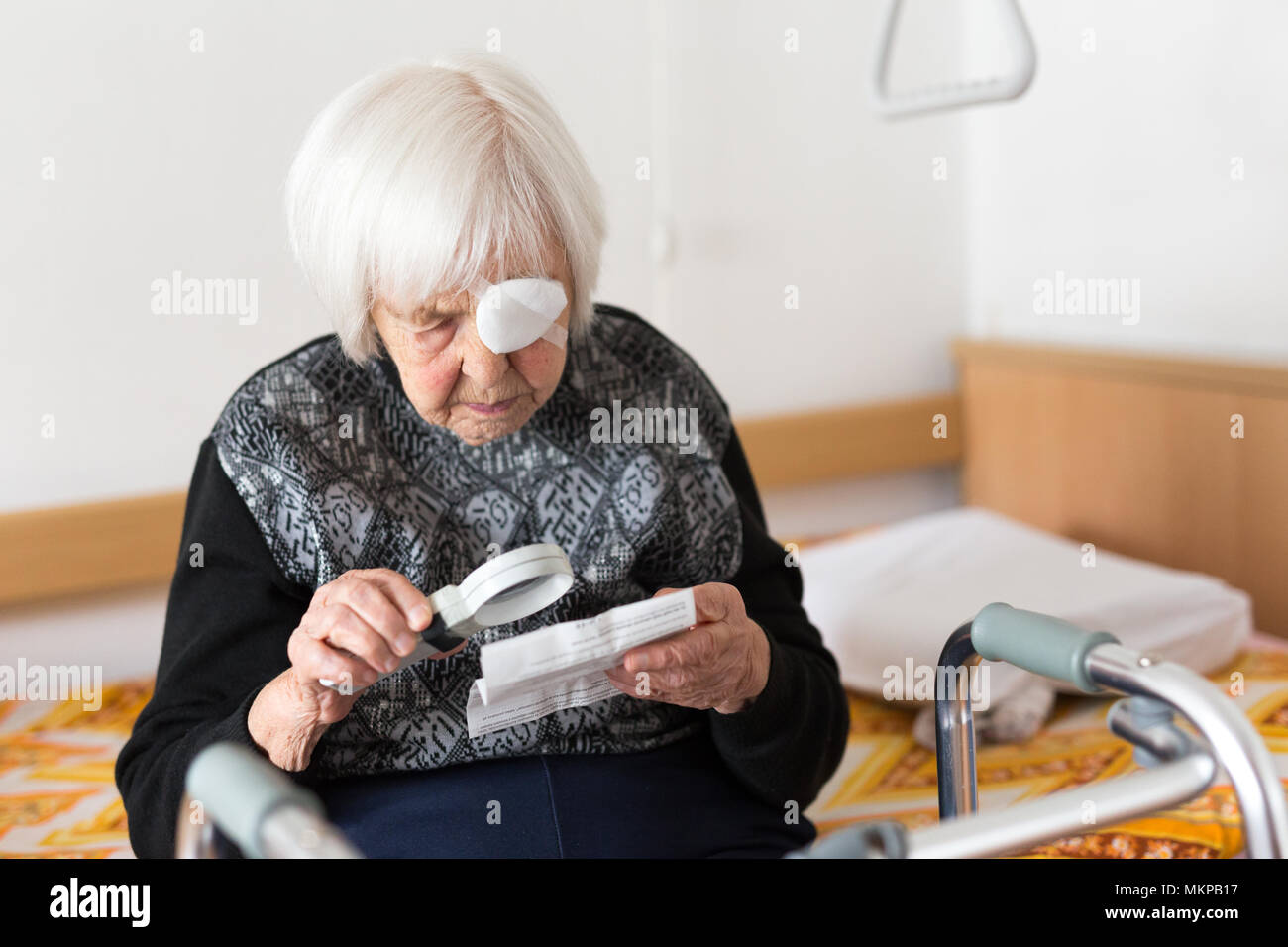 Visually impaired elderly 95 years old woman sitting at the bad trying ...