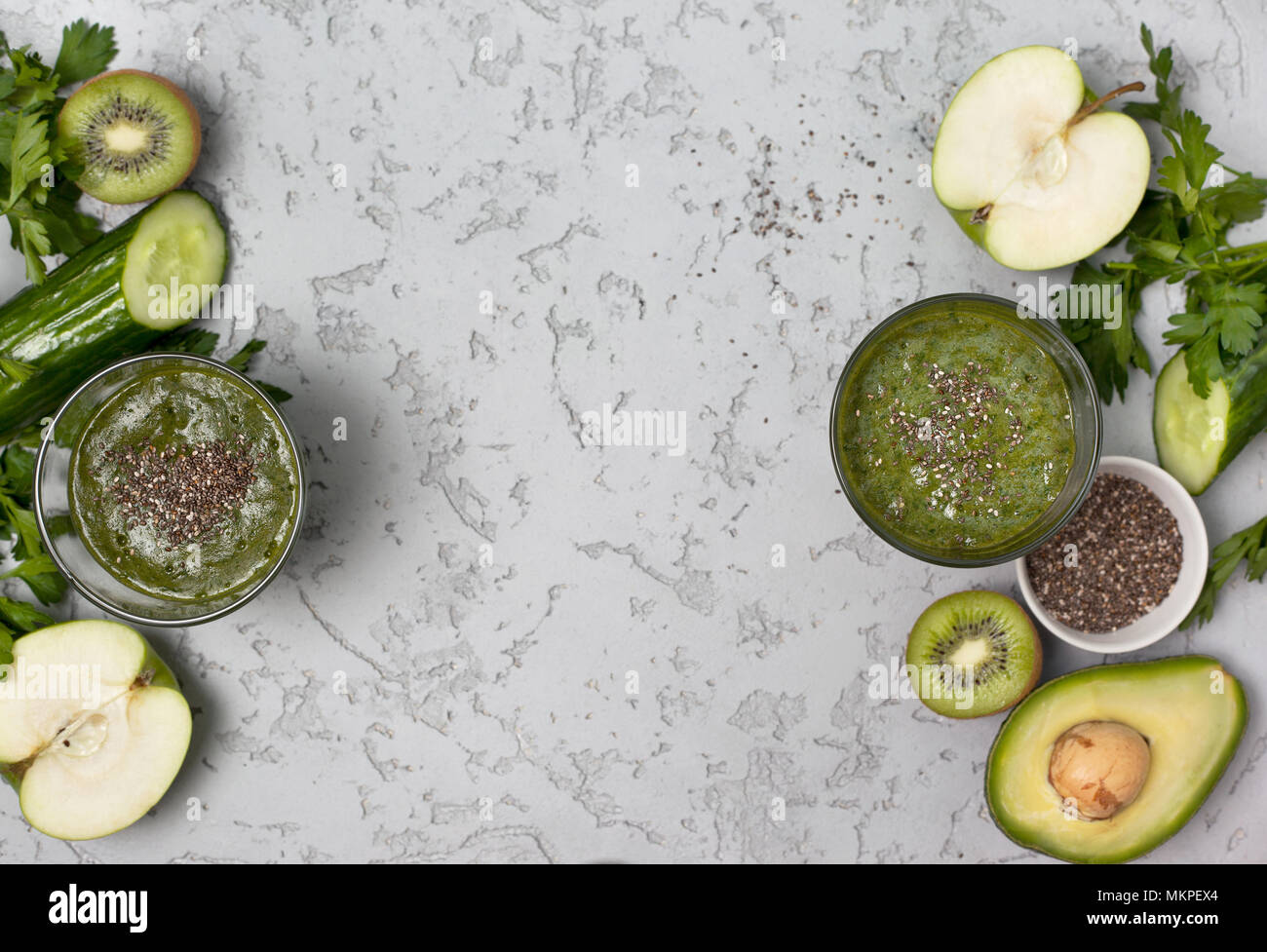 green smoothies in a glass, fresh vegetables, fruits, herbs on a gray ...