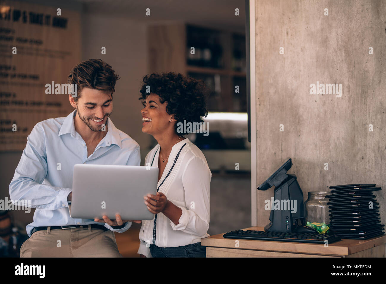 Small business owners using laptop in their restaurant. Smiling man and ...