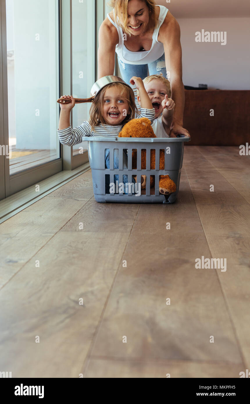 Mother pushing children sitting in laundry basket. Kids enjoying a ...