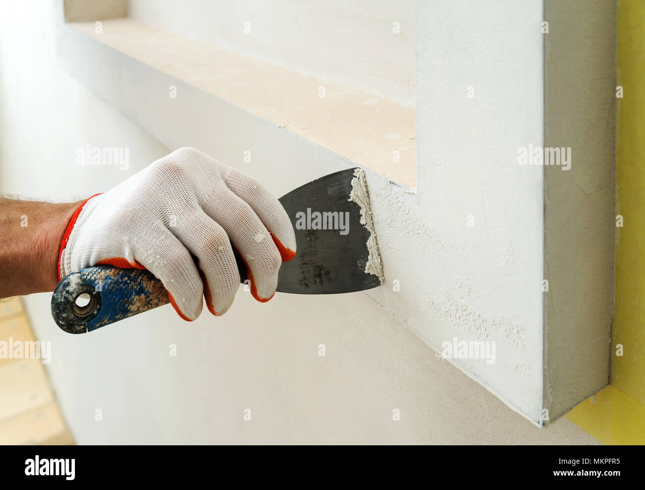 Decorative plaster coating. Man does ragged texture on the wall using a ...