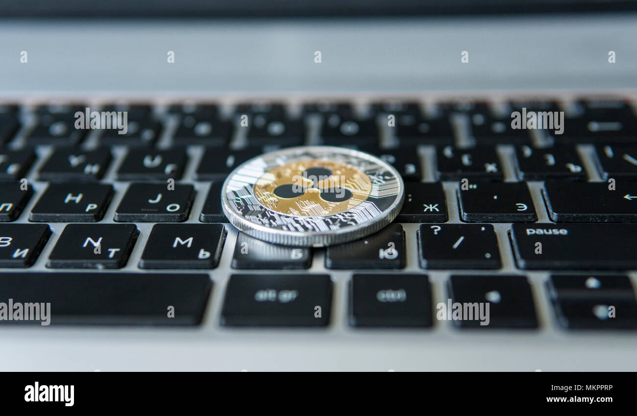 Silver gold ripple coin on a laptop keyboard closeup. Blockchain mining ...