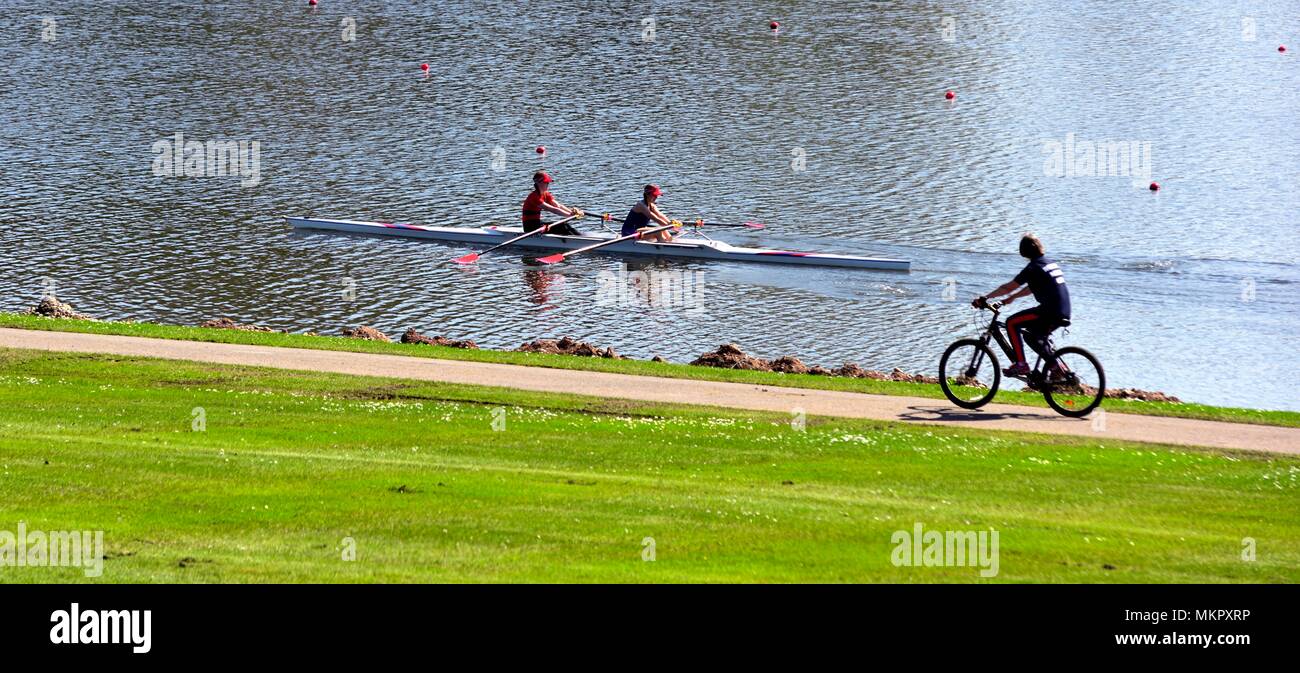 Rowing coach tutor on a bike coaching two rowers at the National water ...